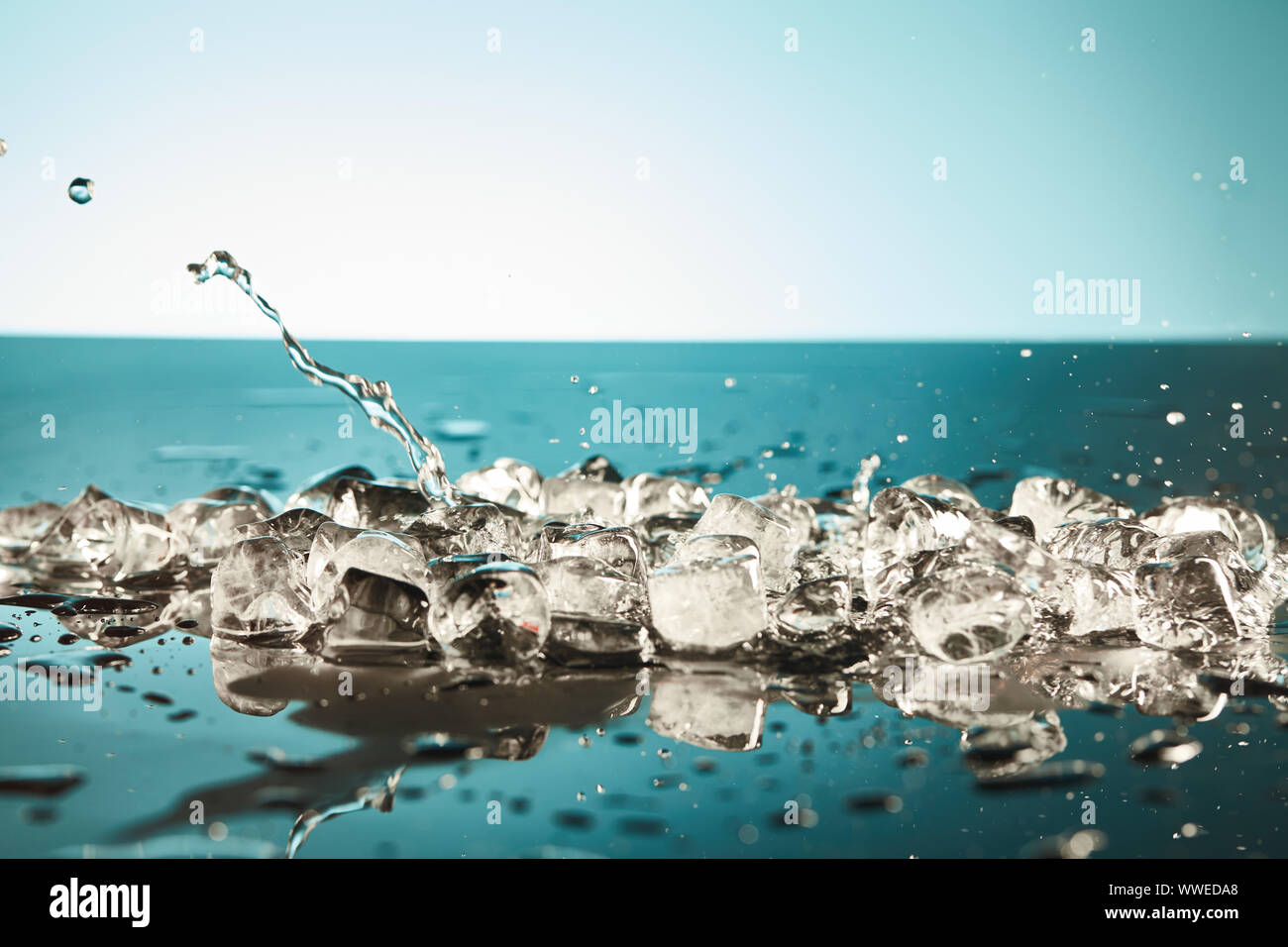 melting ice cubes and water splash on emerald and white background ...