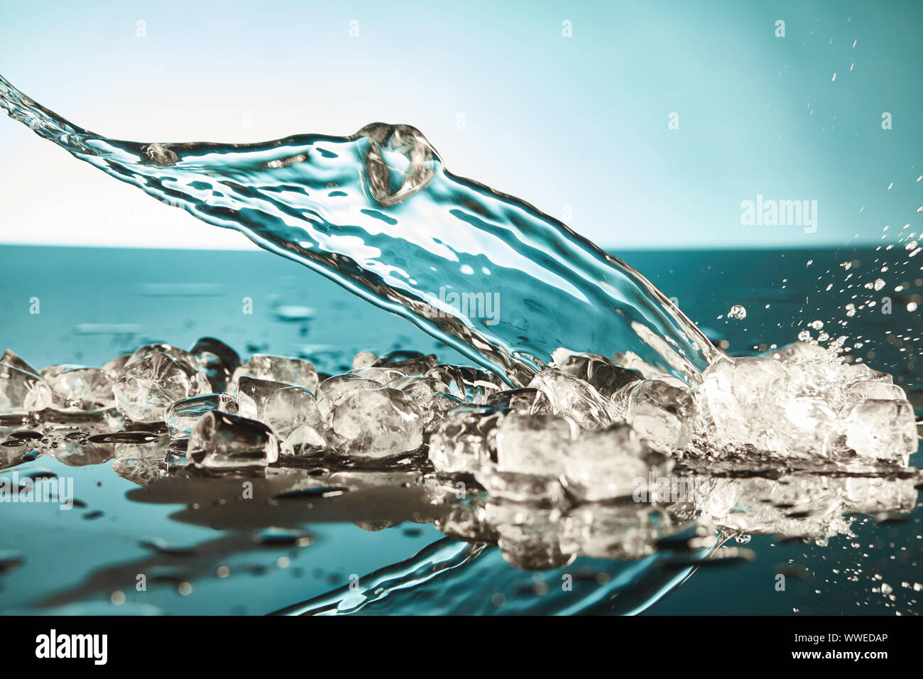 transparent ice cubes and water splash on emerald and white background ...