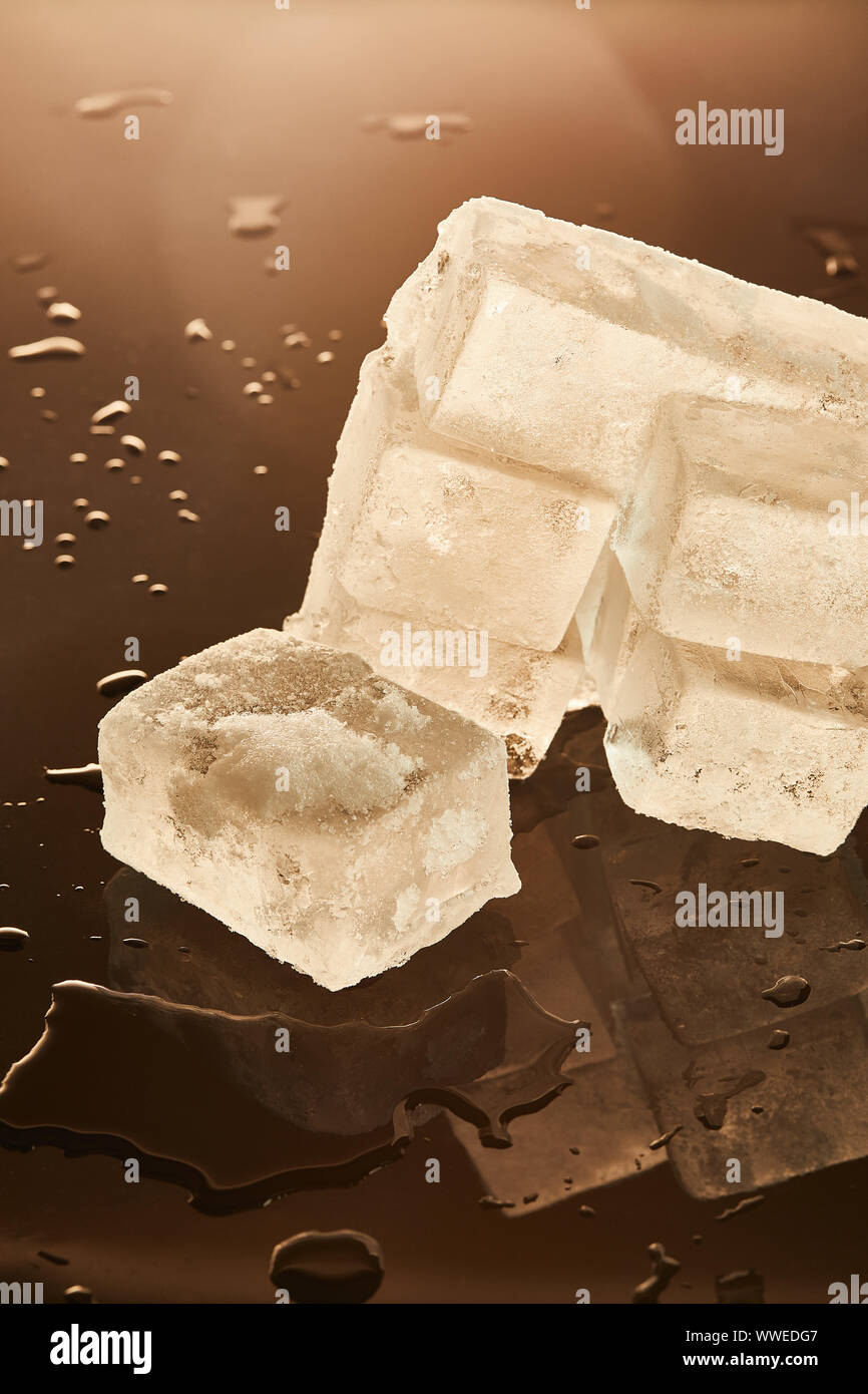 stack of ice cubes with puddles on brown background Stock Photo - Alamy
