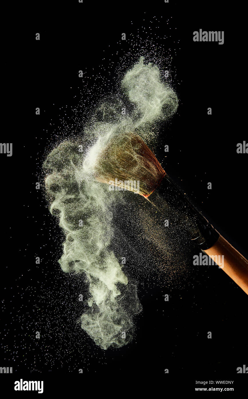 cosmetic brush with colorful powder explosion on black background Stock ...