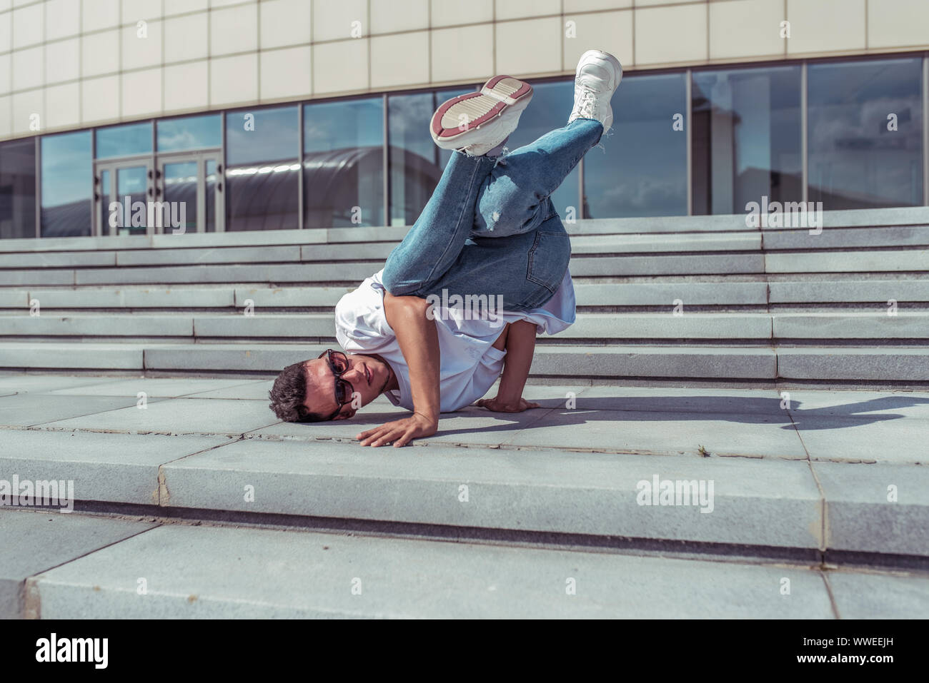 Young stylish man on steps, guy a dancer, in summer in city, dancing ...