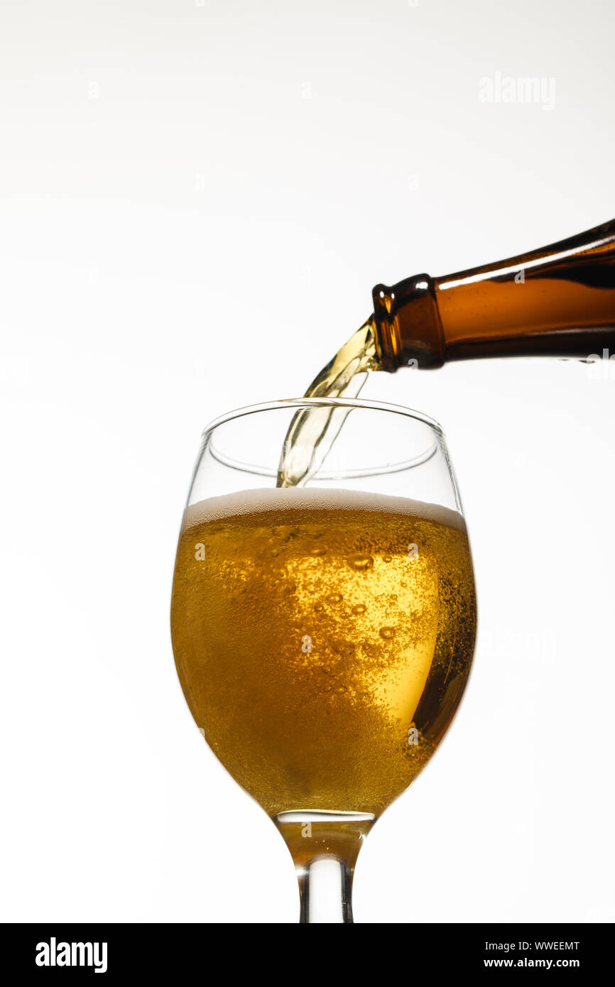 Low Angle View Of Fresh Beer Pouring From Bottle Into Glass Isolated On