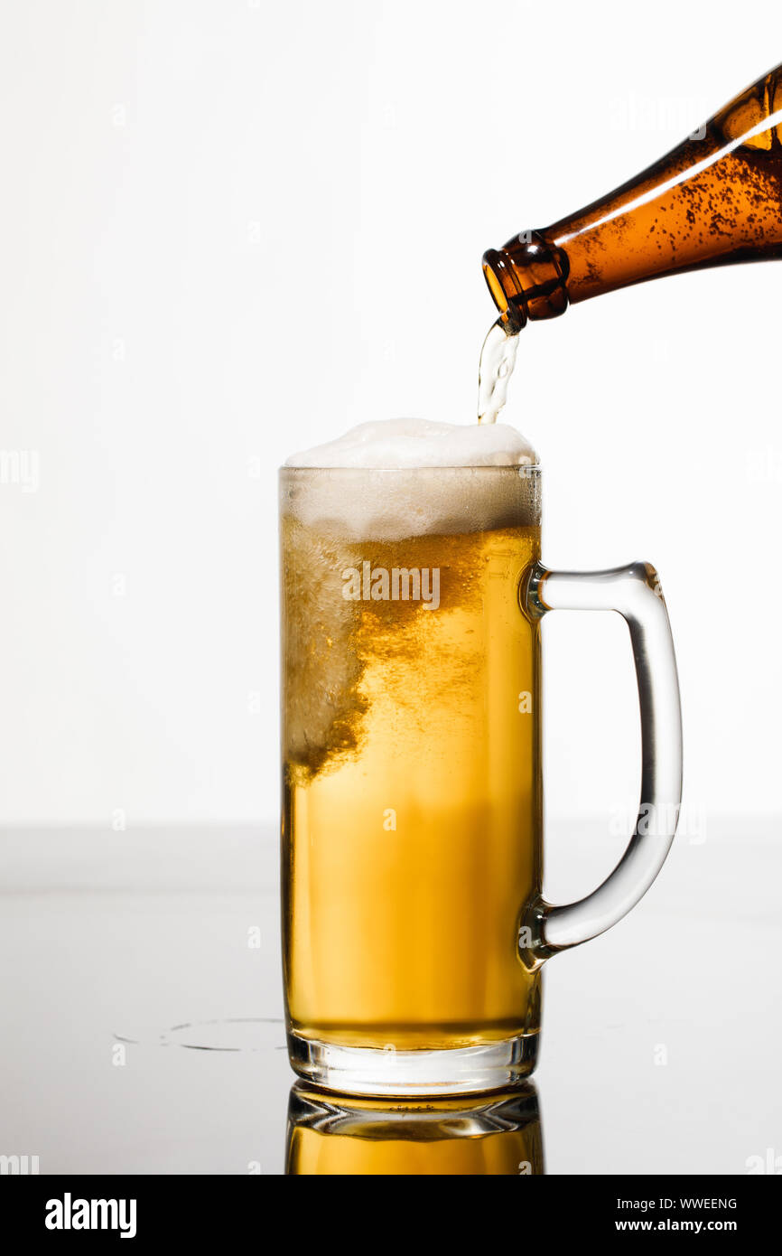 Beer Pouring From Bottle Into Glass With Bubbles Isolated On White