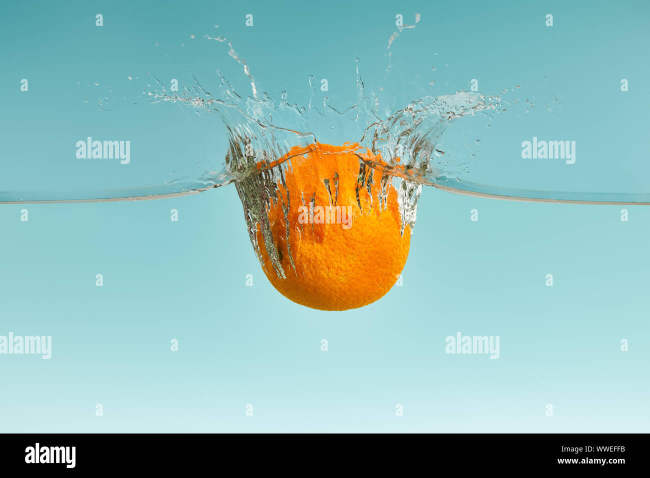 fresh orange falling in water with splash on blue background Stock ...