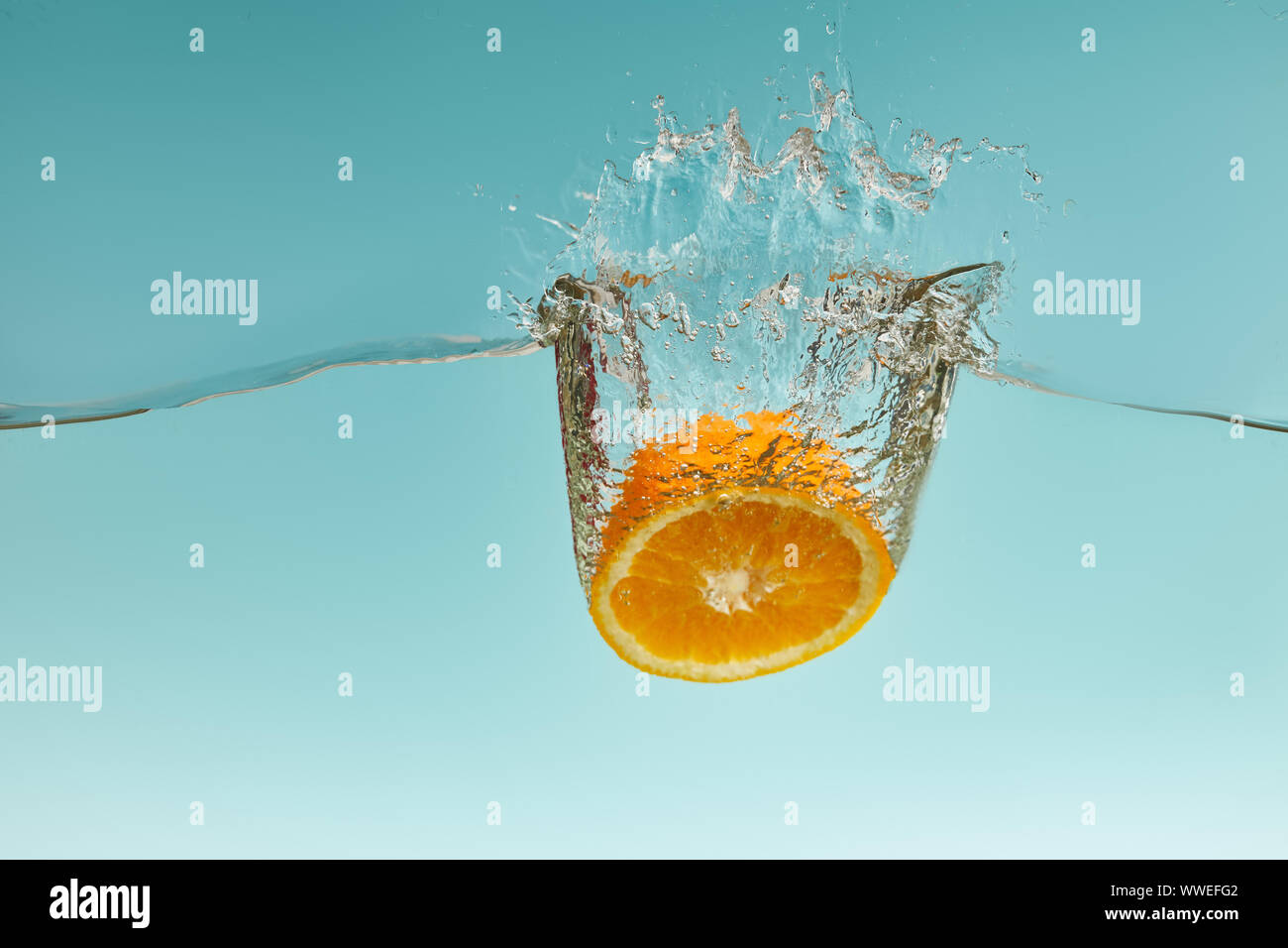 ripe orange half falling in water with splash on blue background Stock ...