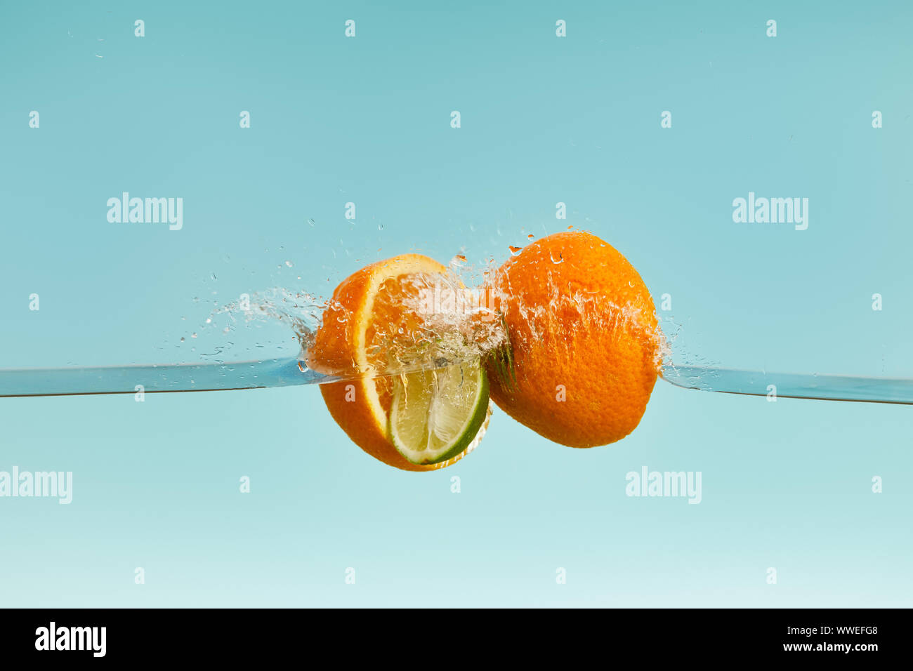 ripe orange halves falling in water with drops on blue background Stock ...
