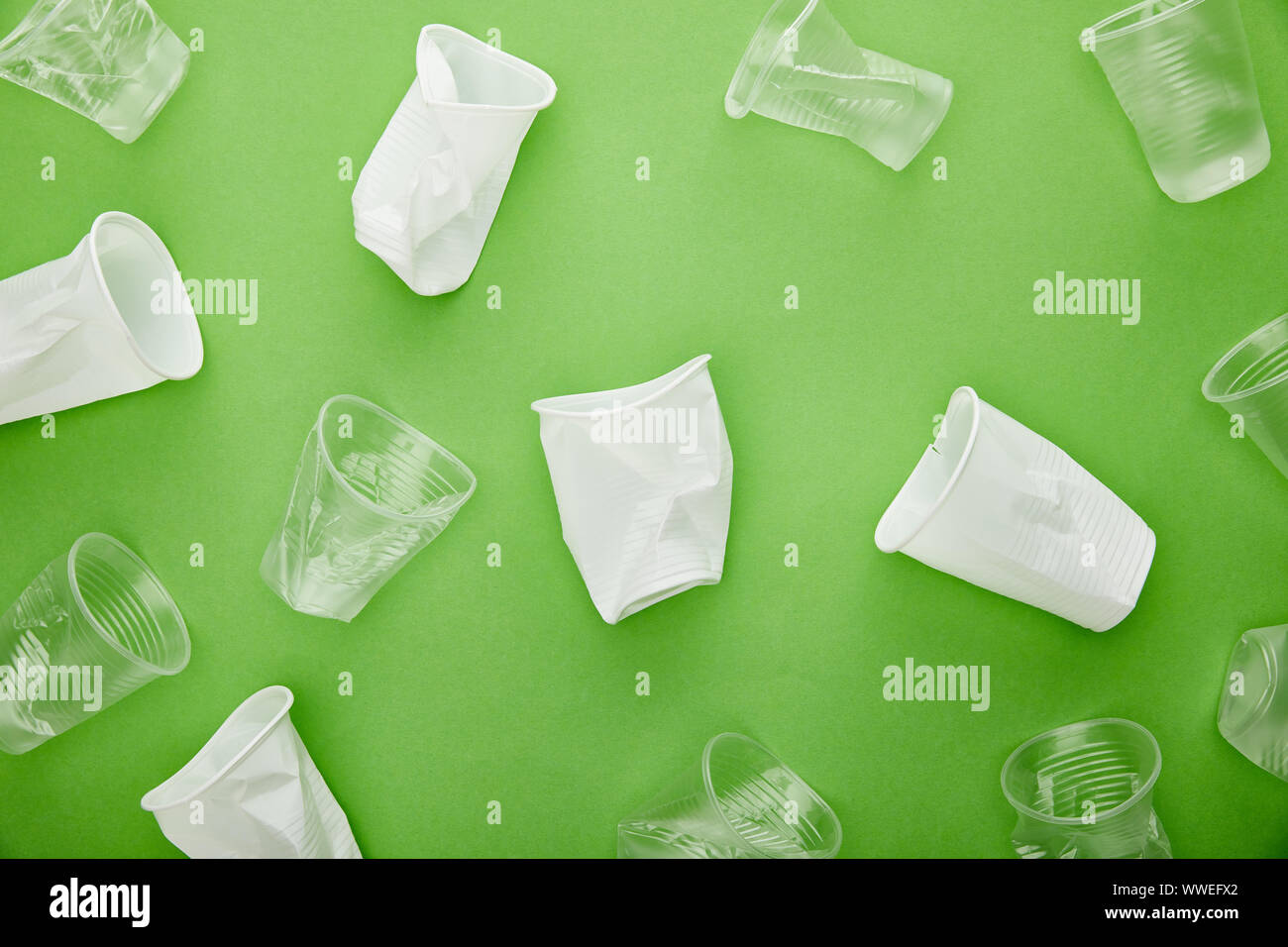 top view of disposable white and transparent plastic cups on green ...
