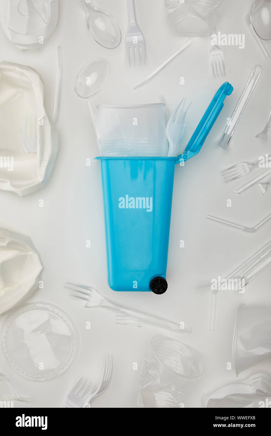 top view of blue recycle bin with crumpled disposable cup, fork, spoons ...