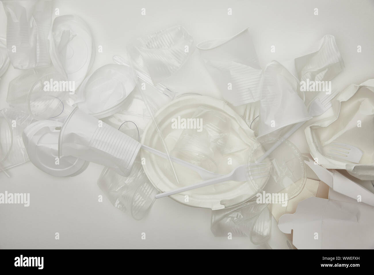 top view of crumpled plastic cups, plates and cardboard container on ...