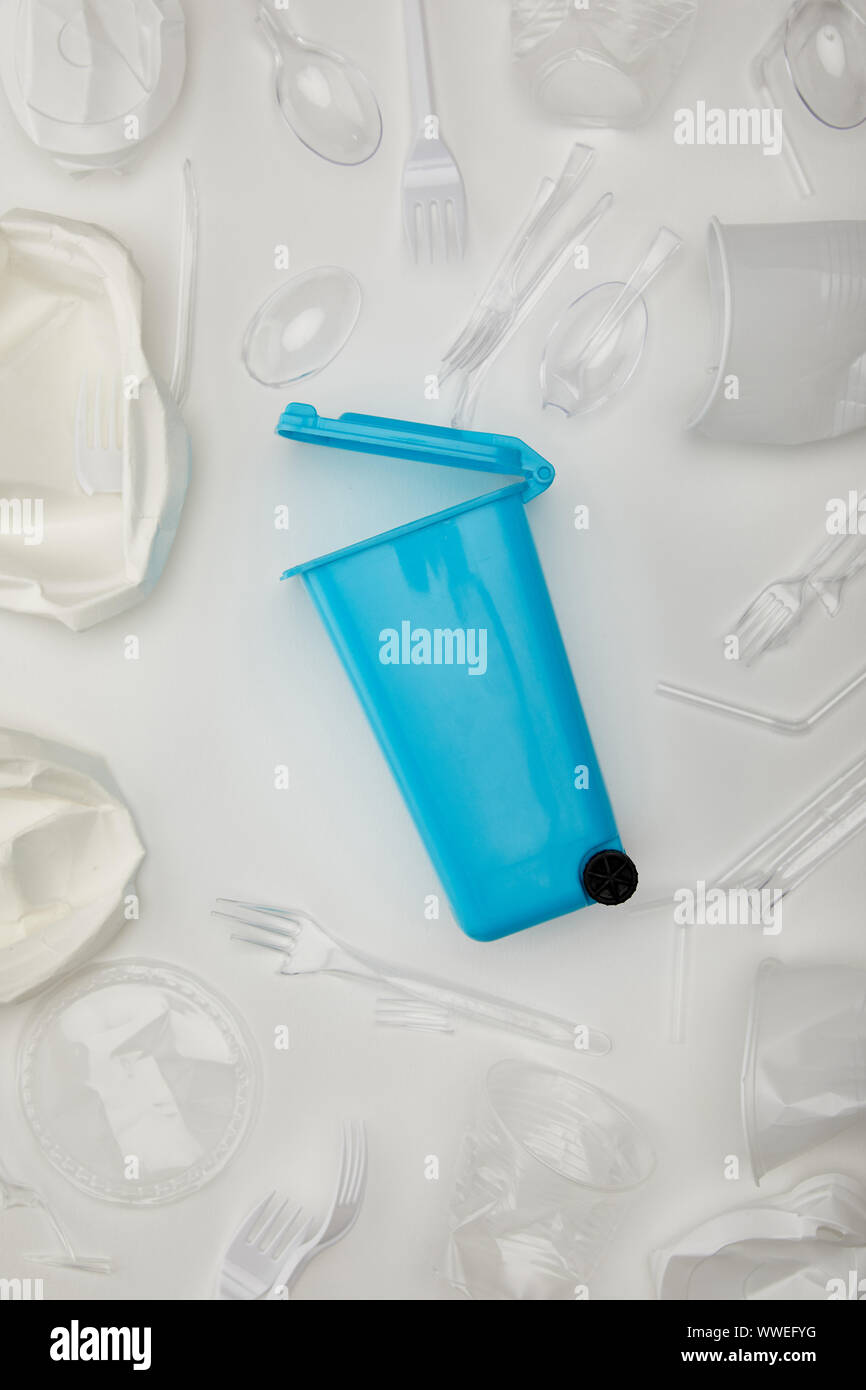 top view of blue recycle bin, crumpled disposable cups, forks, spoons ...