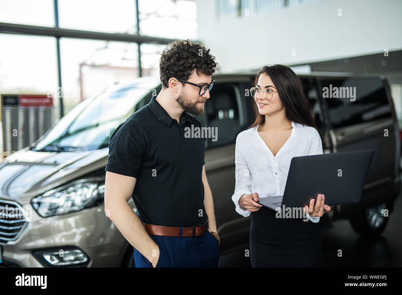 Portrait of a female car seller and her potential buyer looking at ...