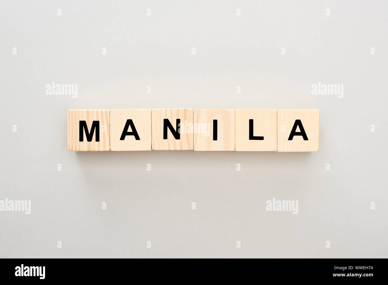 top view of wooden blocks with Manila lettering on grey background ...