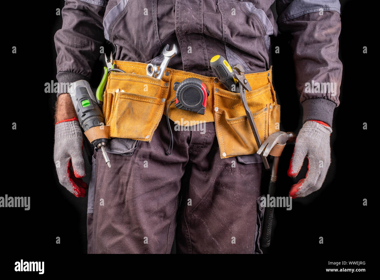 Production worker with tool belt. Screwdriver in worker kekek. Dark ...