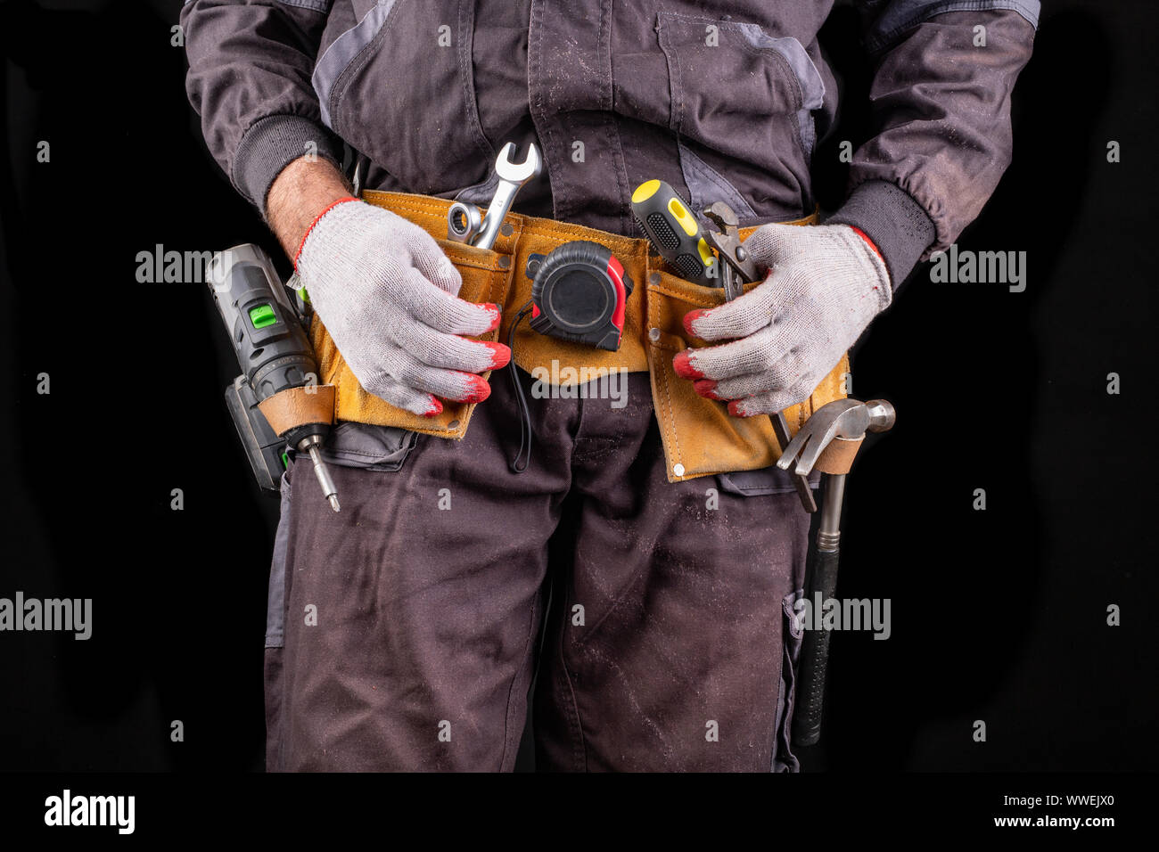 Production worker with tool belt. Screwdriver in worker kekek. Dark ...