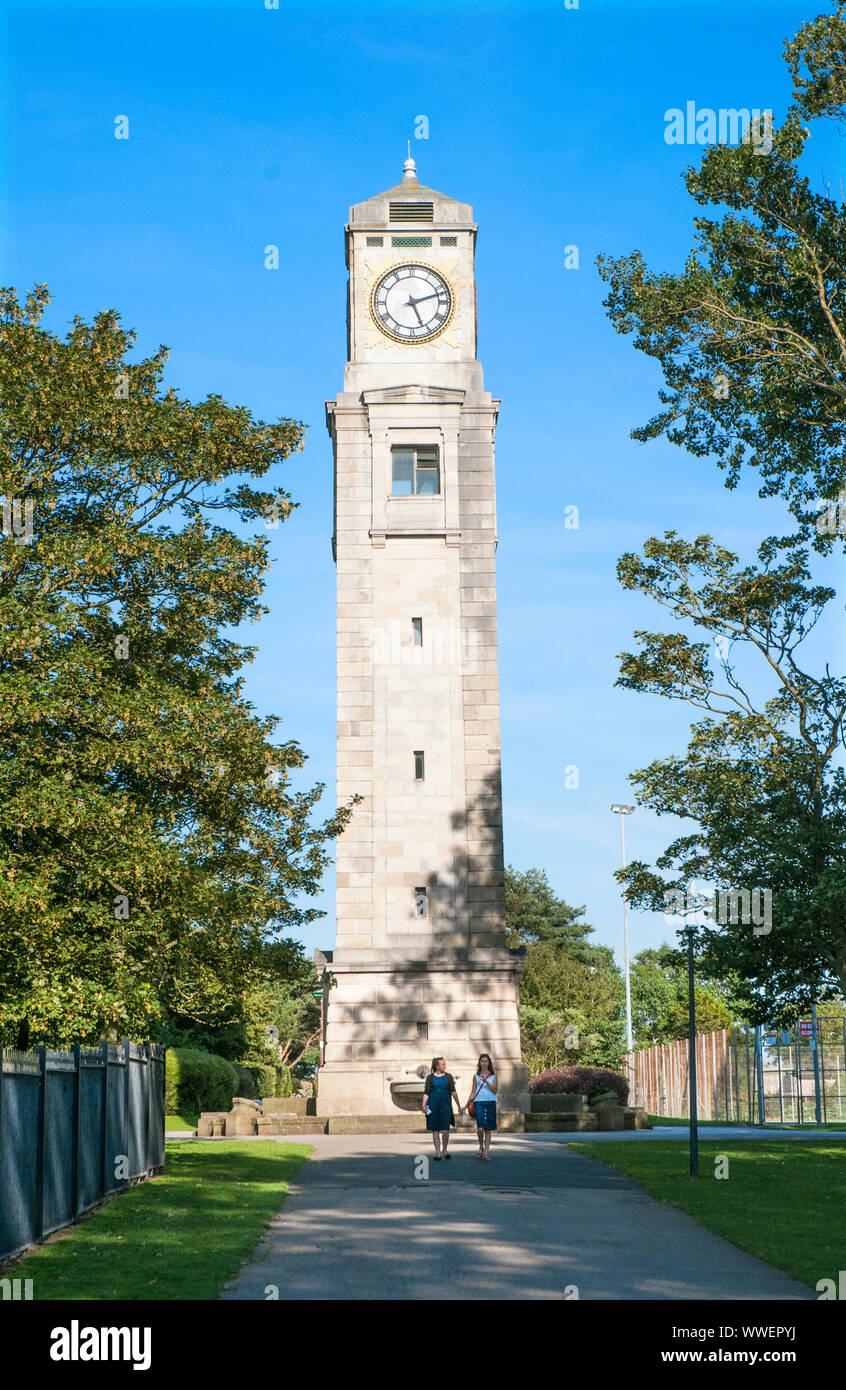 Two ladies walking in front of the Cocker Clock Tower on a sunny day in ...