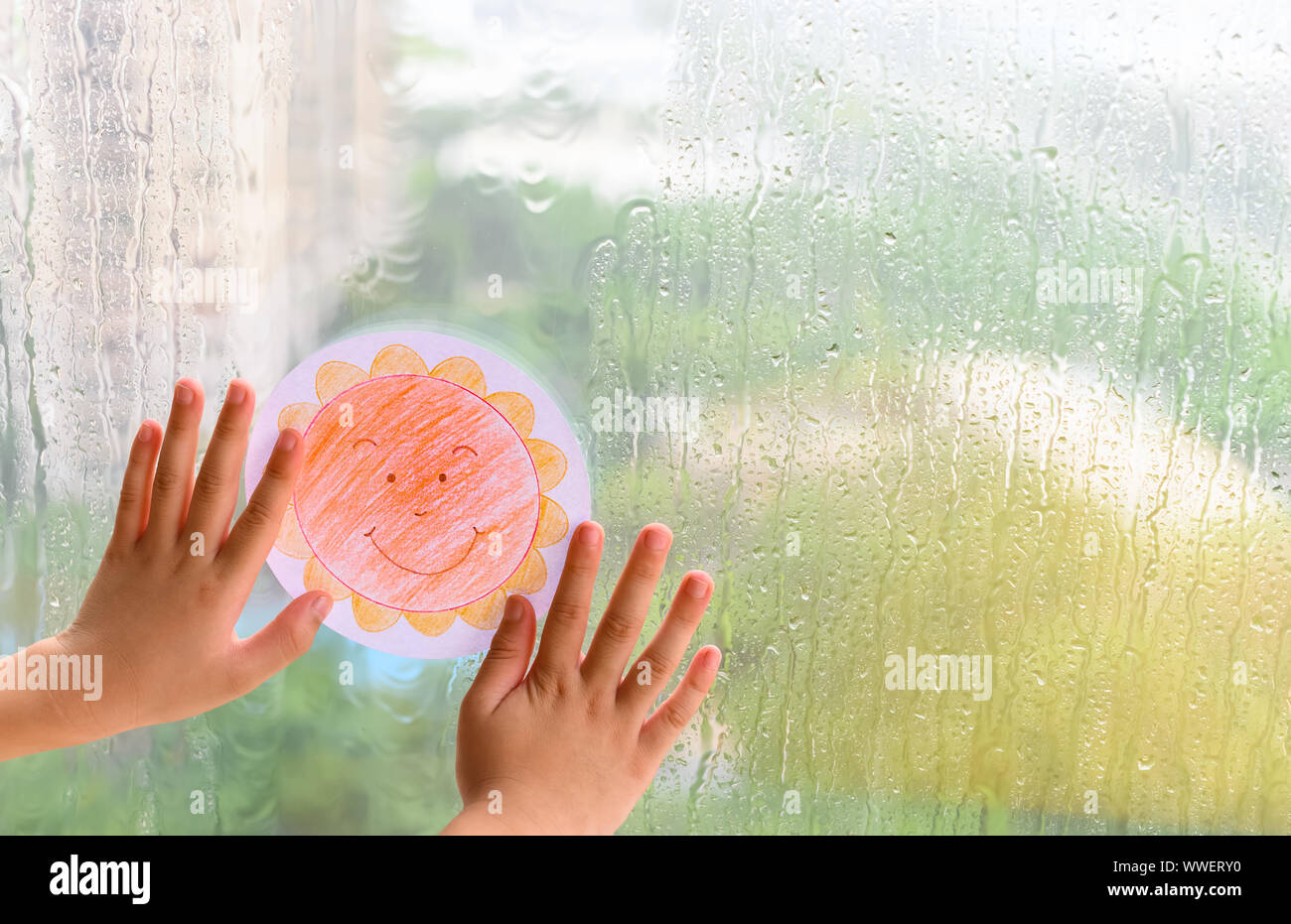 kid holding picture of a smiling sun in a raining day concept of faith ...
