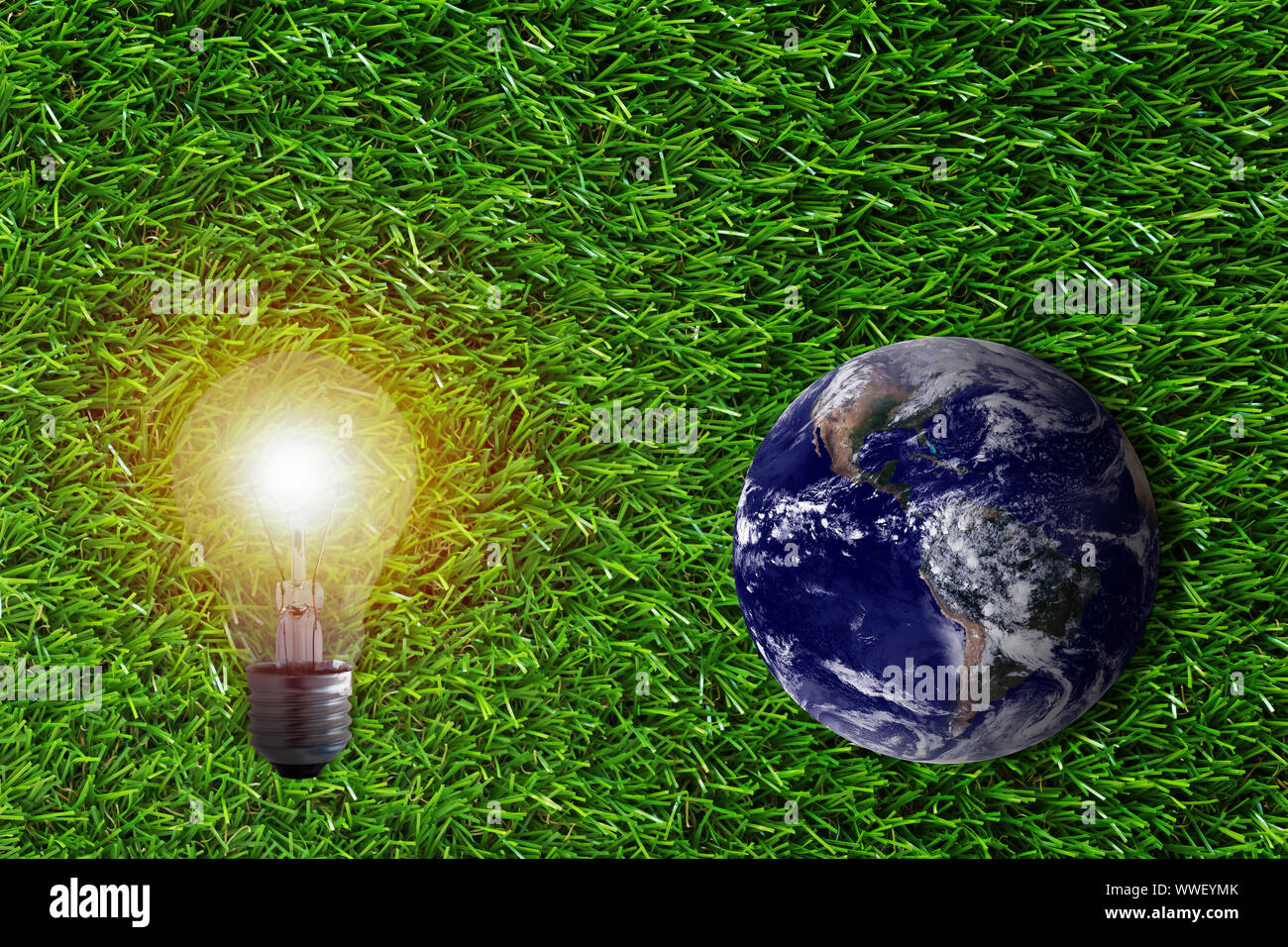 Green energy concept, the earth and light bulb on grass background ...
