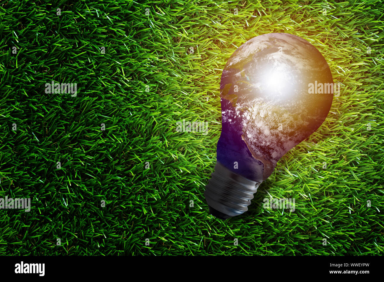 Green energy concept, the earth and light bulb on grass background ...