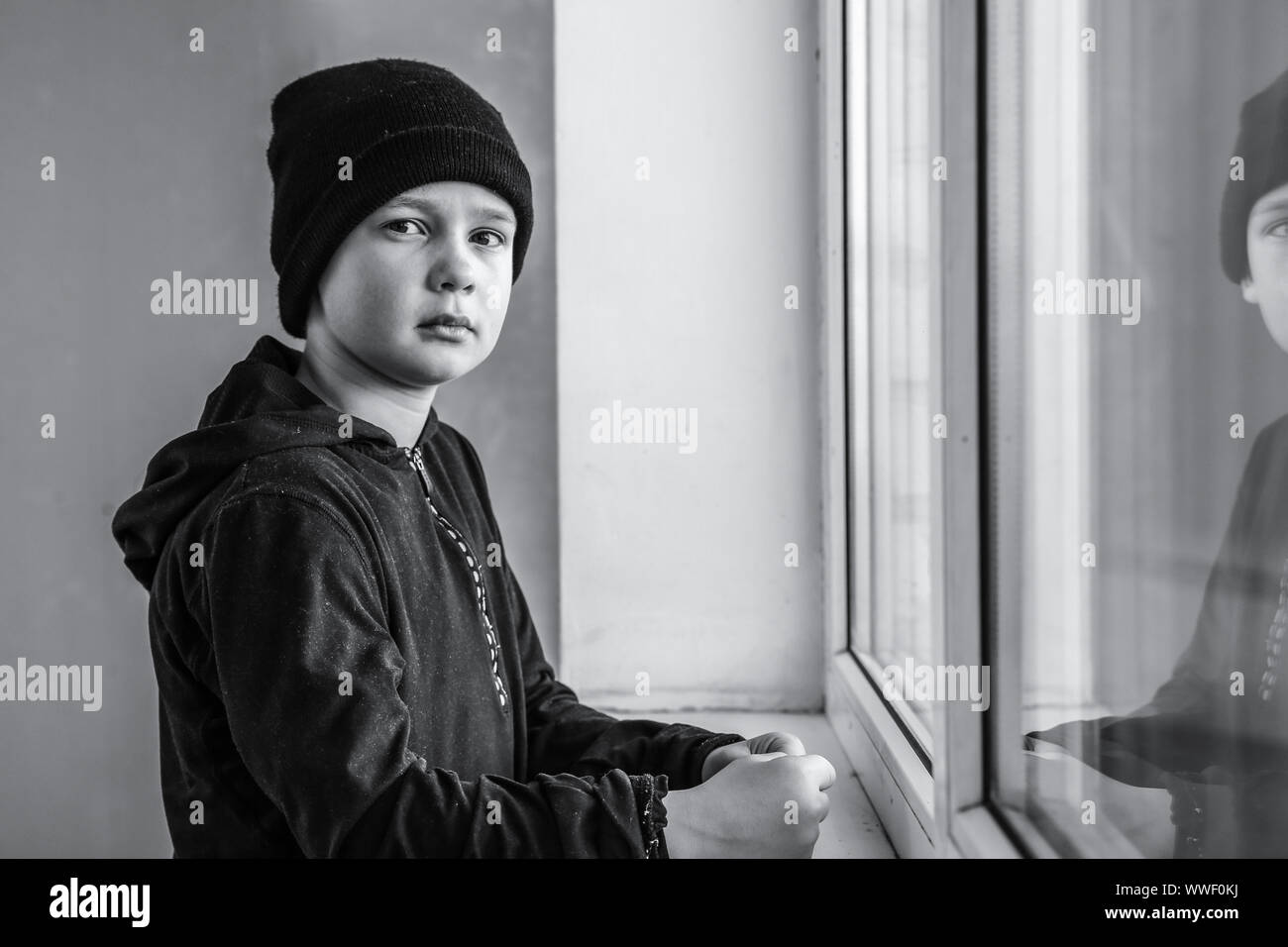 Homeless little boy near window indoors Stock Photo - Alamy