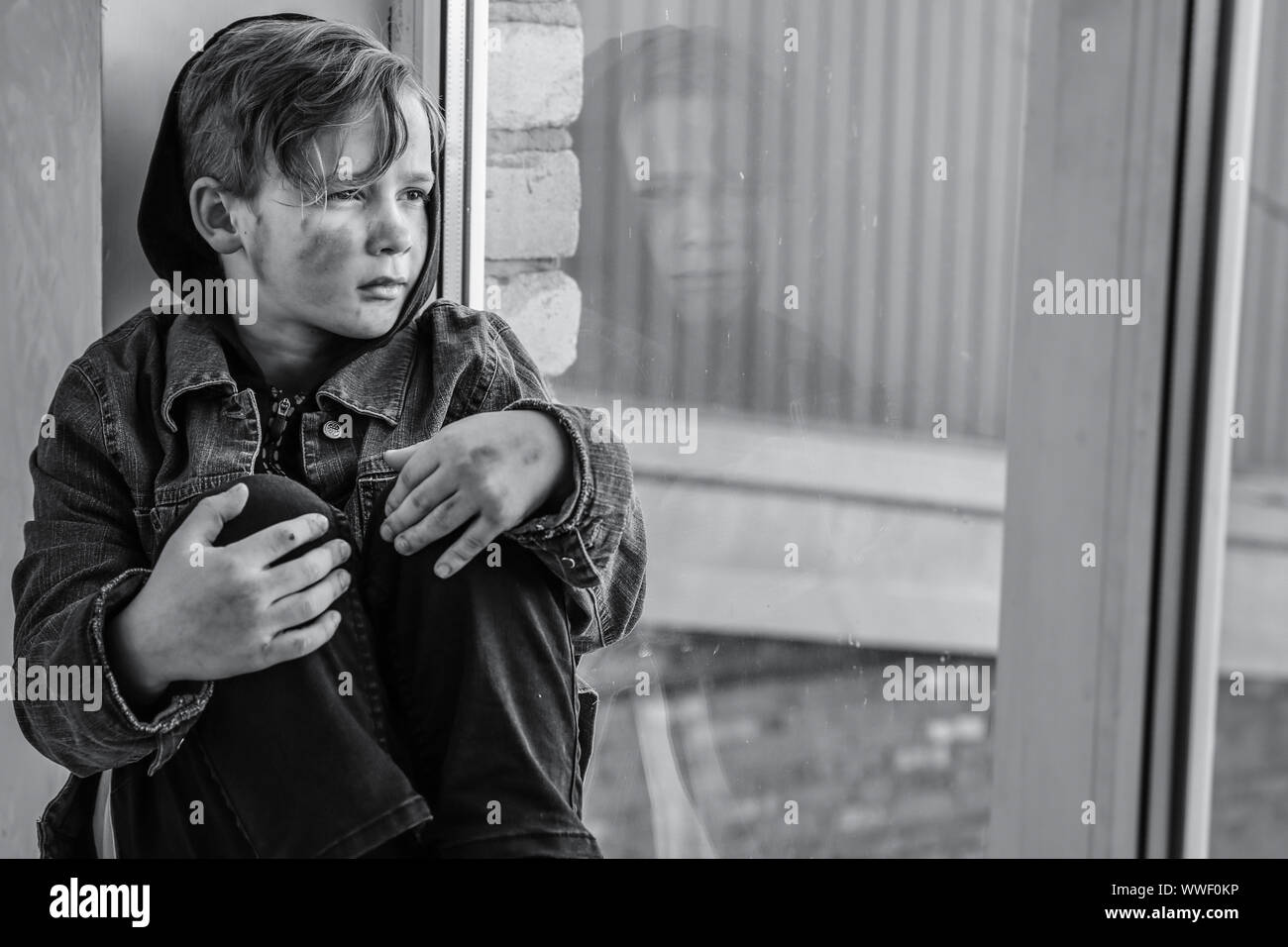 Homeless little boy sitting on window sill indoors Stock Photo - Alamy