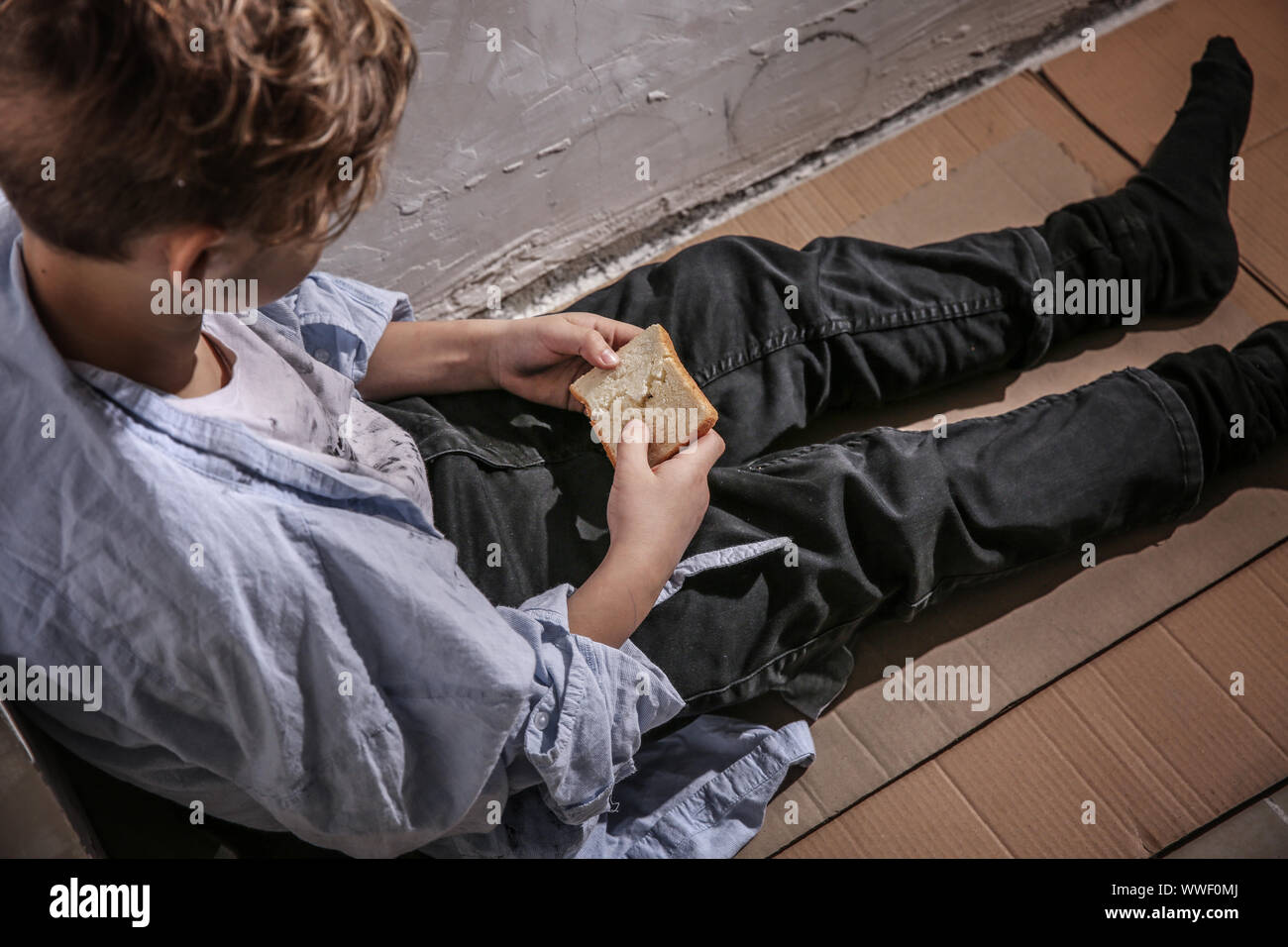 Homeless little boy with bread sitting on floor Stock Photo - Alamy