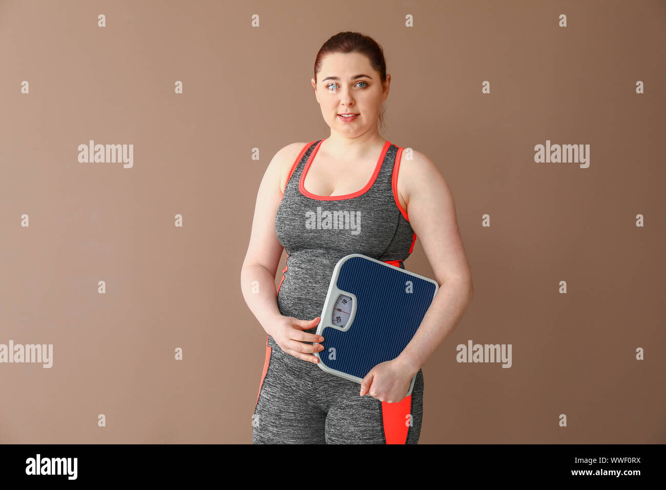 Overweight woman with scales on color background. Weight loss concept ...