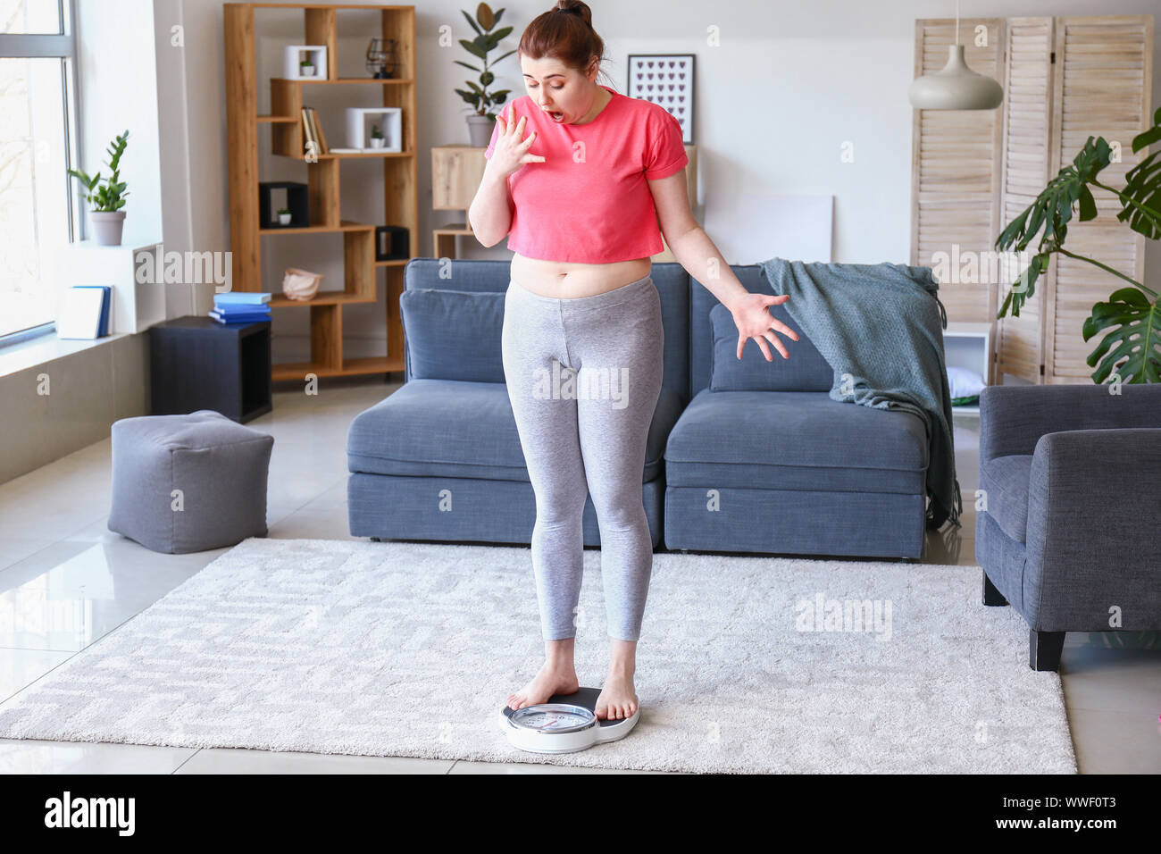 Shocked overweight woman standing on scales at home. Weight loss ...