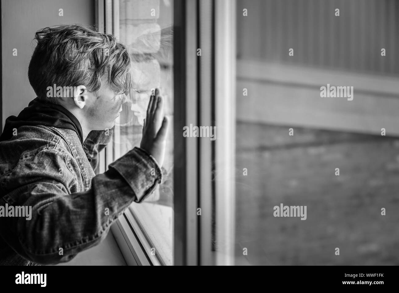 Homeless little boy near window indoors Stock Photo - Alamy