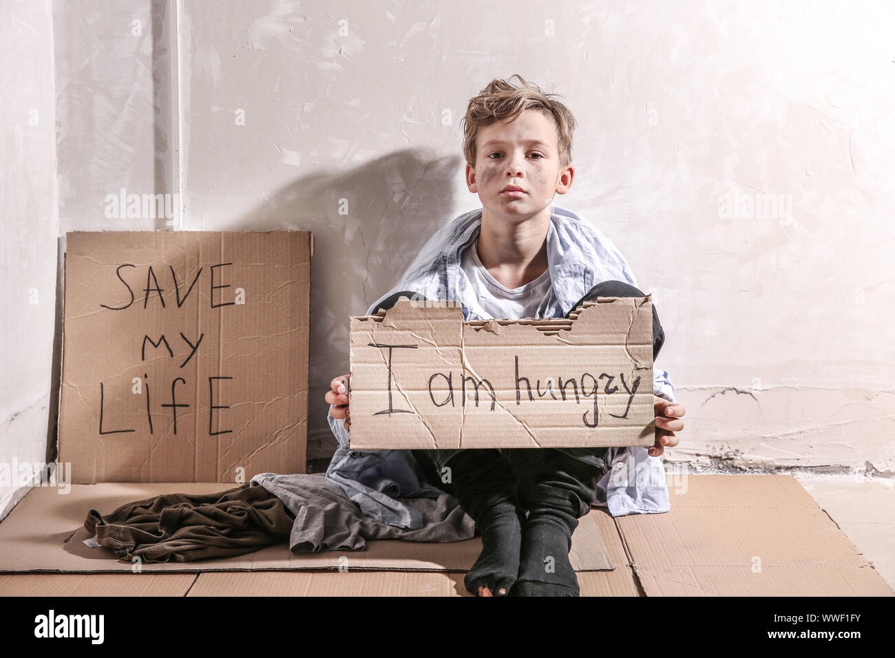 Homeless little boy begging for food indoors Stock Photo - Alamy