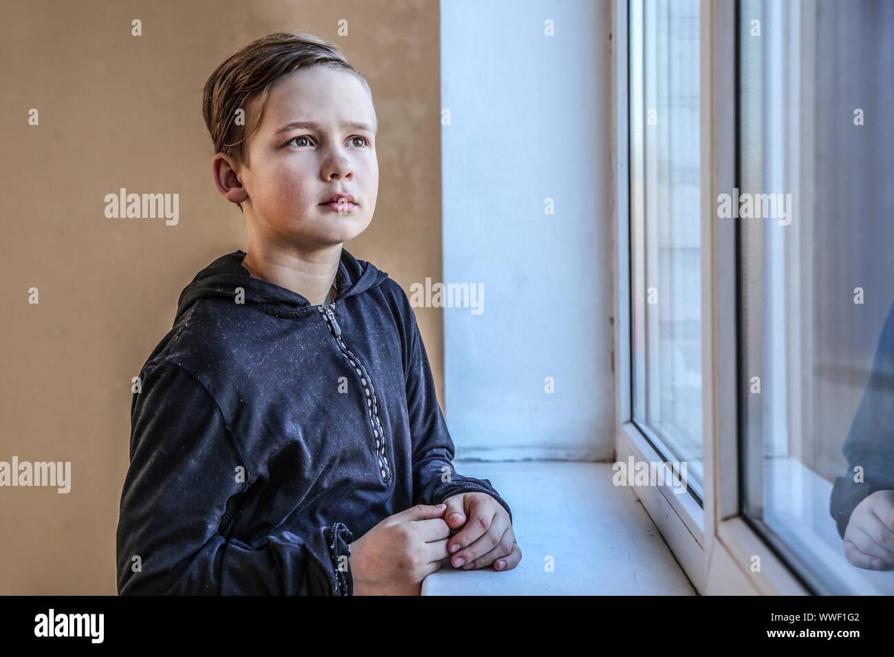 Homeless little boy near window indoors Stock Photo - Alamy