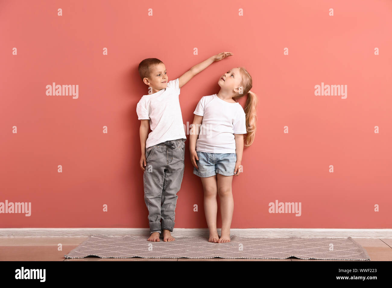 Little children measuring height near wall Stock Photo - Alamy