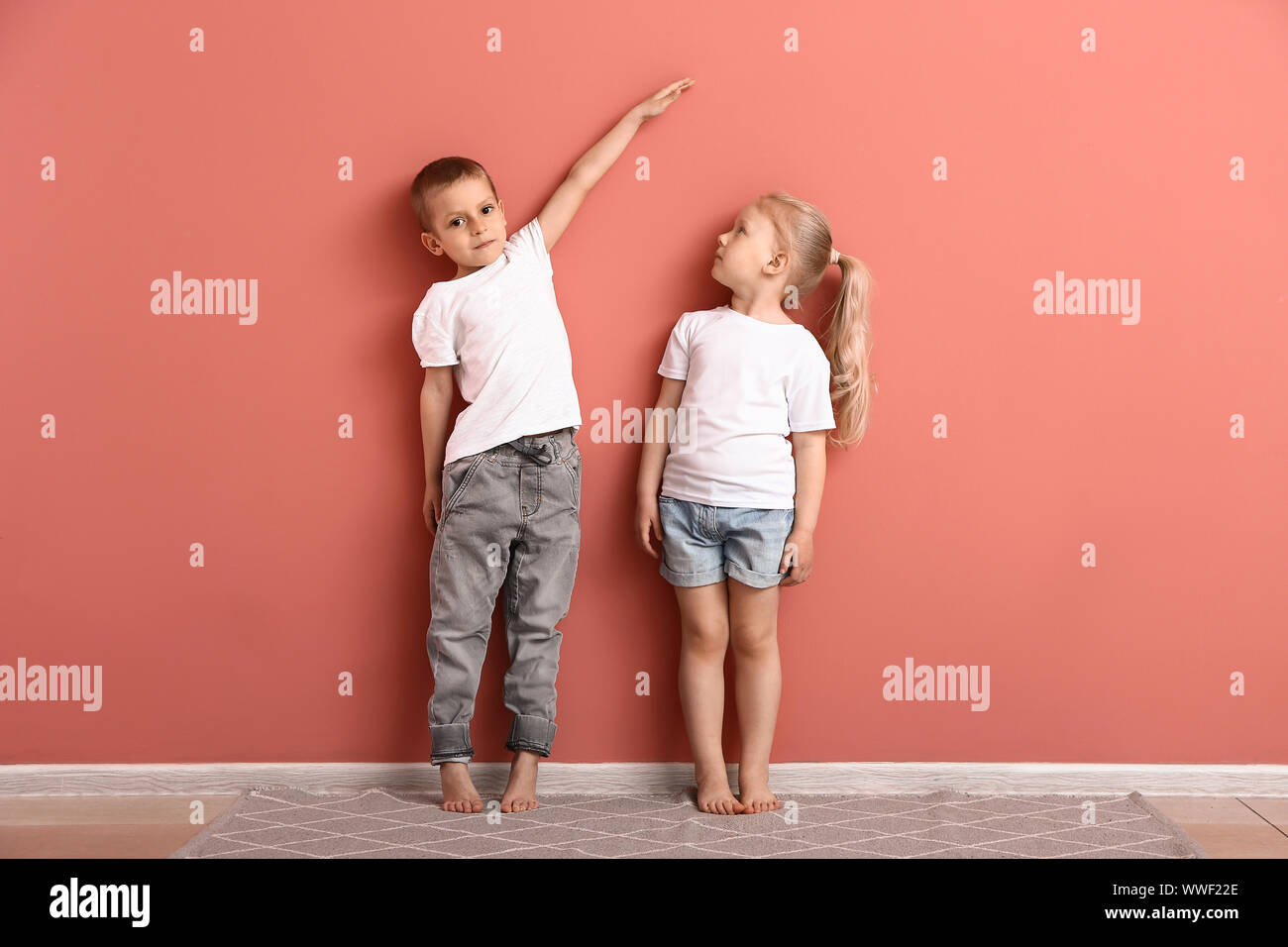 Little children measuring height near wall Stock Photo - Alamy