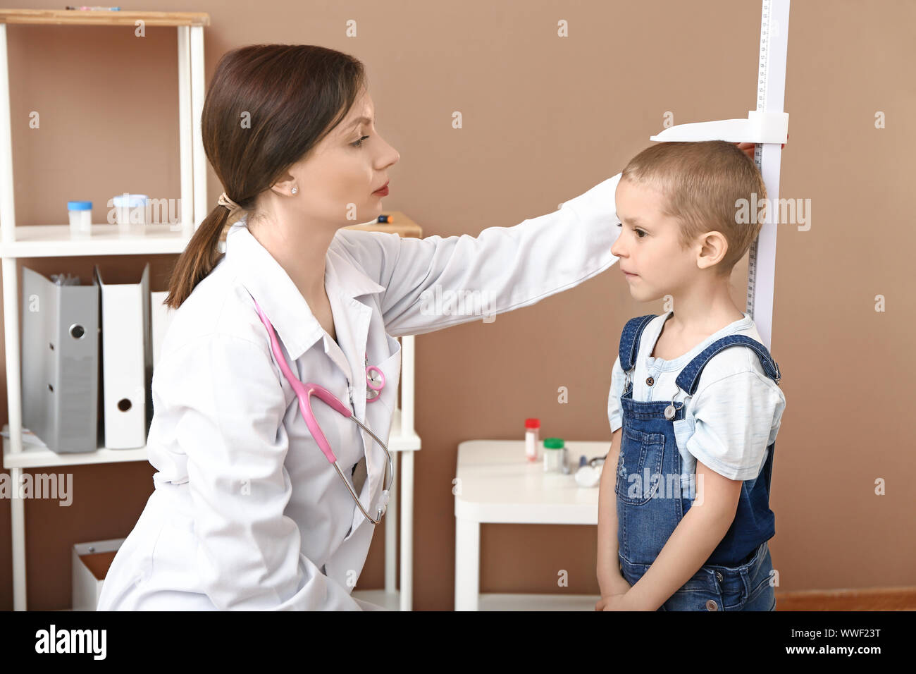 Female doctor measuring height of little boy in hospital Stock Photo ...