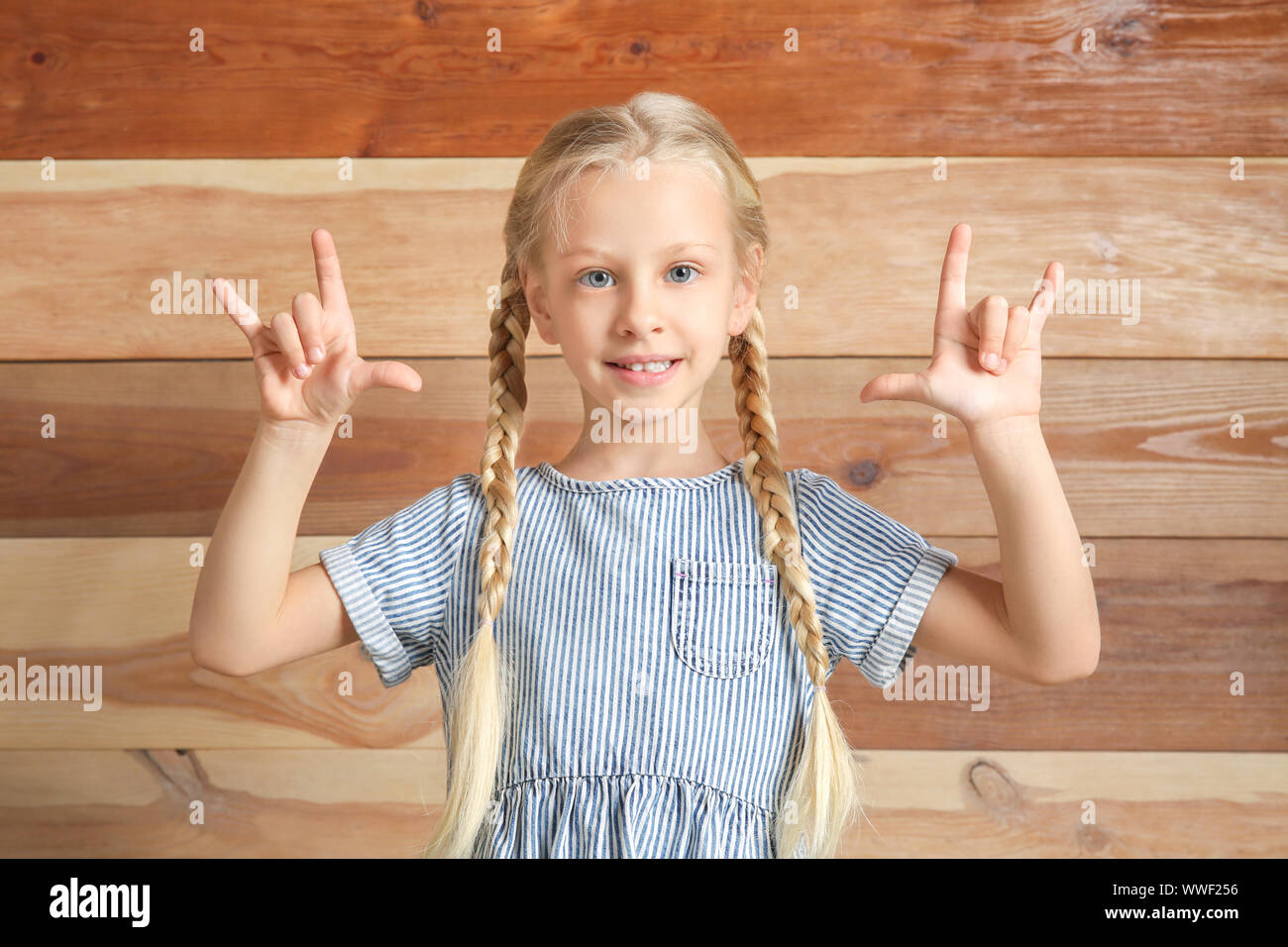Little deaf mute girl using sign language on wooden background Stock ...