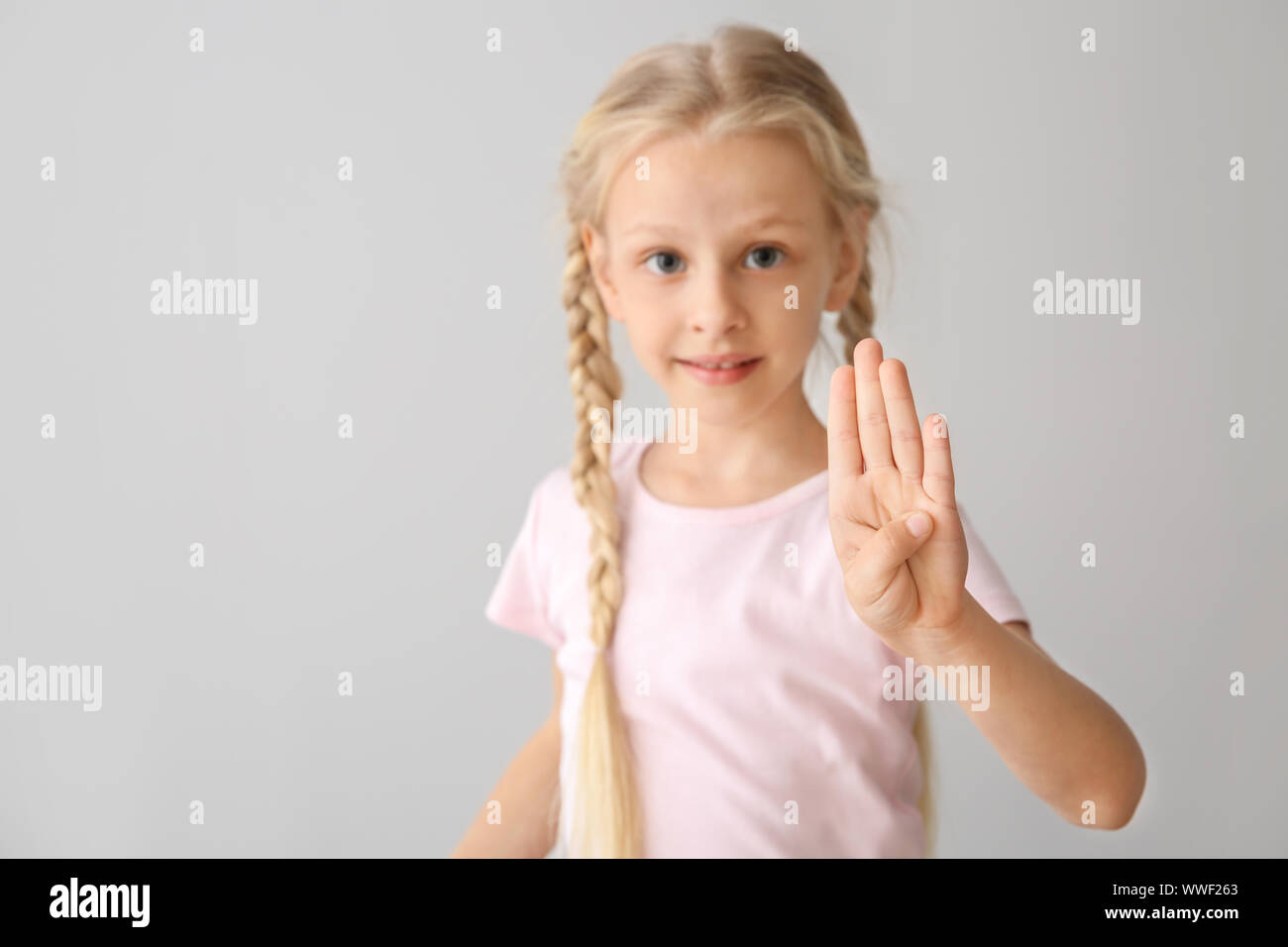 Little deaf mute girl using sign language on light background Stock ...