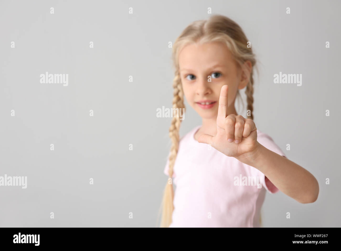 Little deaf mute girl using sign language on light background Stock ...