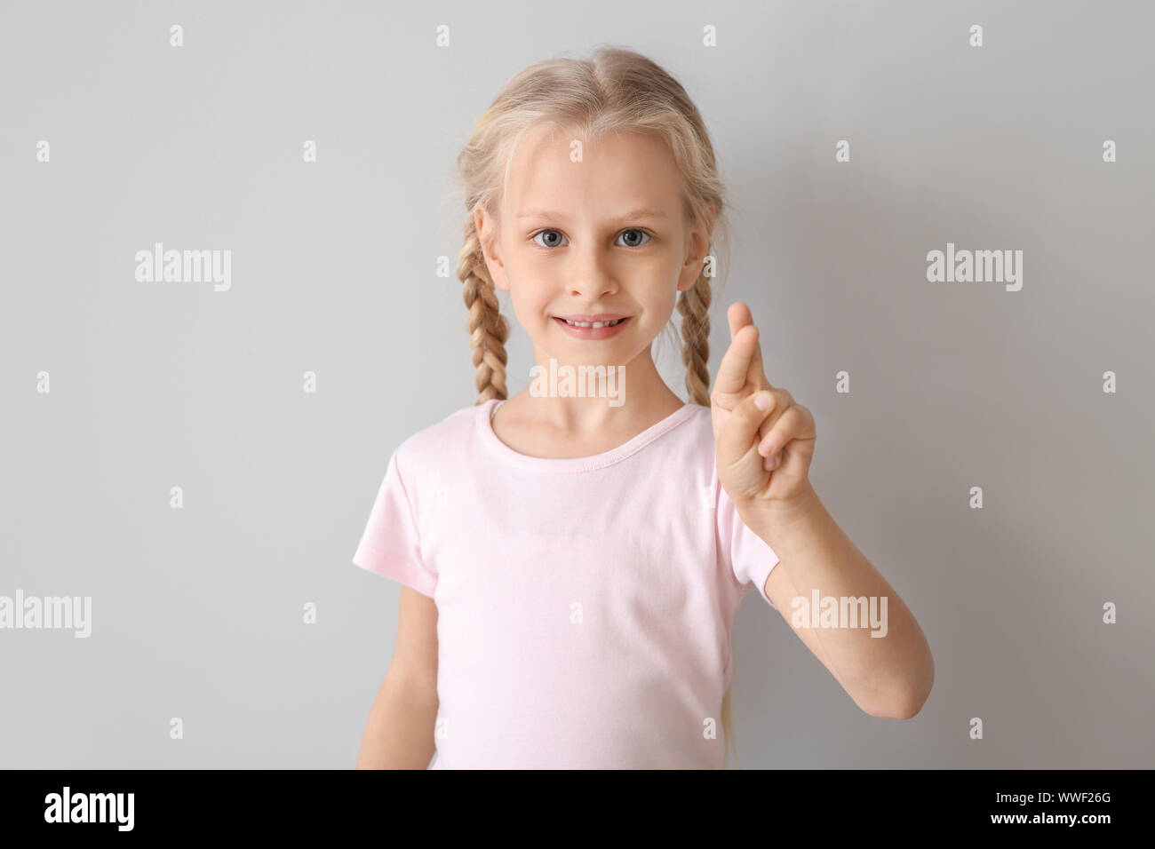 Little deaf mute girl using sign language on light background Stock ...