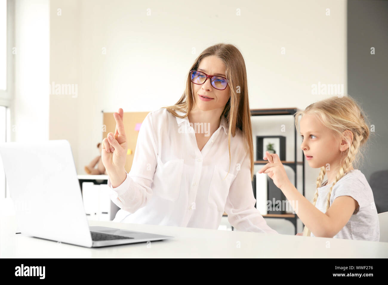 Mother teaching her deaf mute daughter to use sign language at home ...