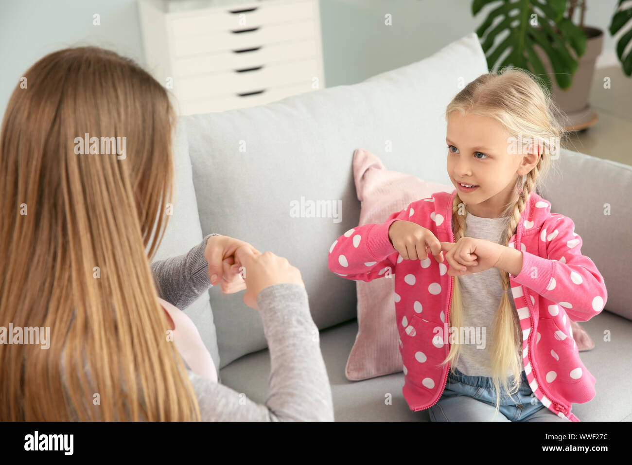 Mother teaching her deaf mute daughter to use sign language at home ...