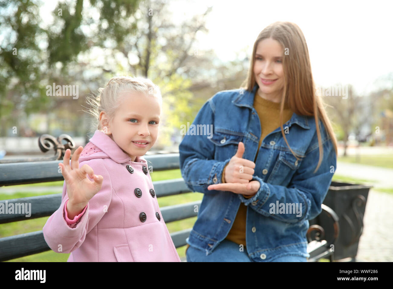 Little deaf mute girl and her mother using sign language outdoors Stock ...