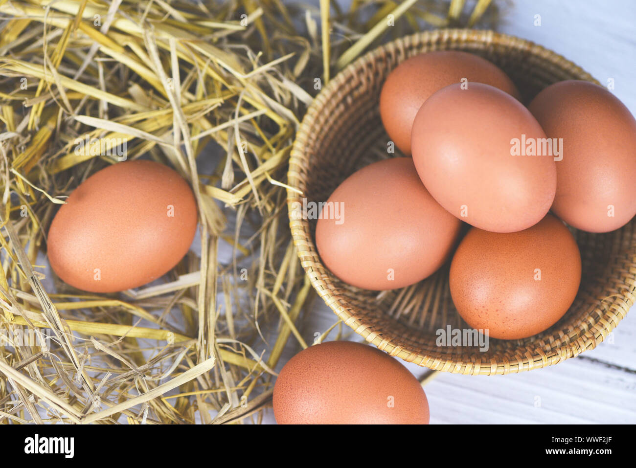 Fresh egg on basket and straw with wooden table background top view ...