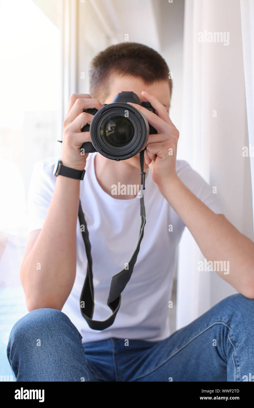 Teenage boy with photo camera near window Stock Photo - Alamy