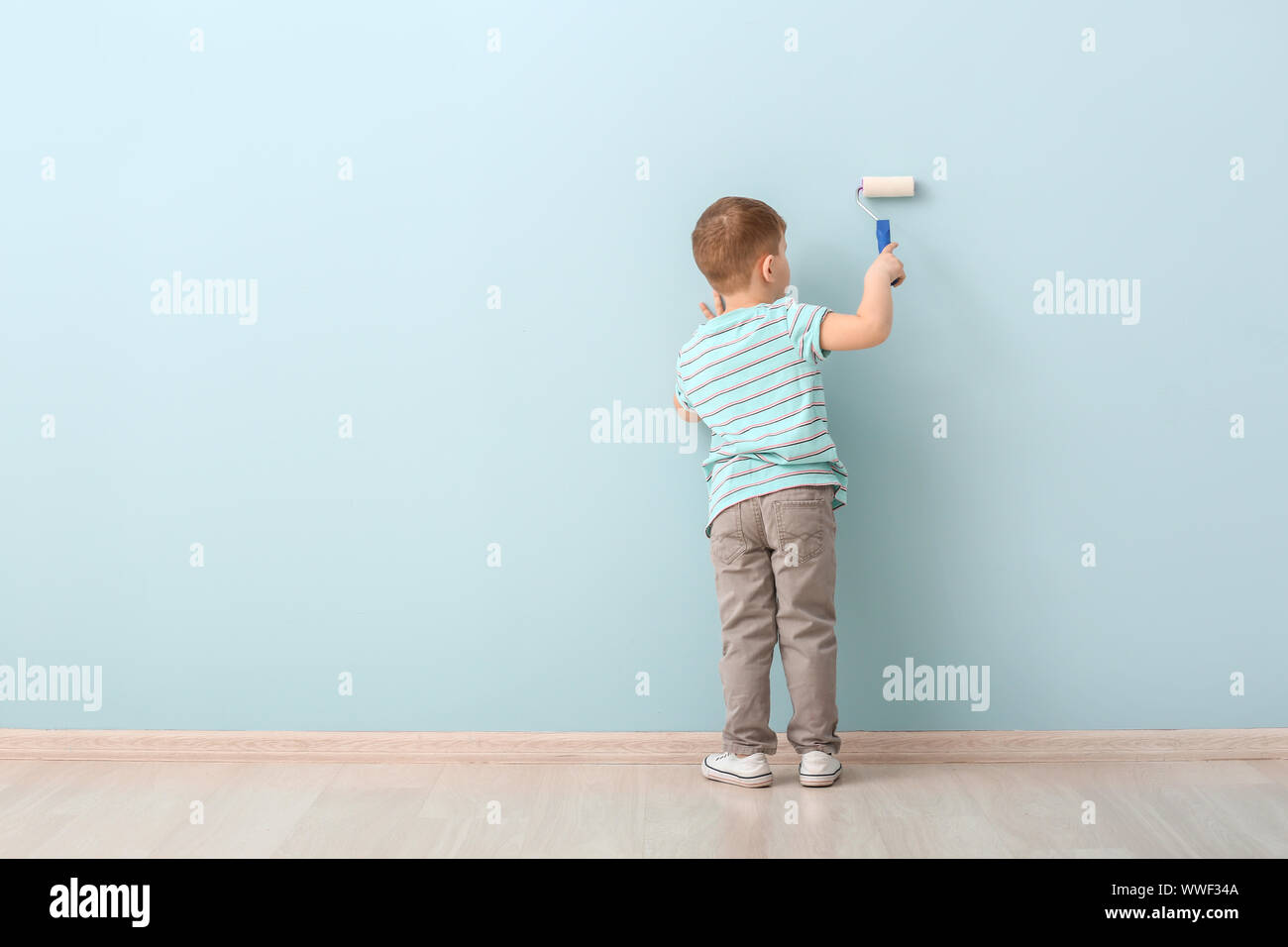 Cute little boy painting wall in room Stock Photo - Alamy