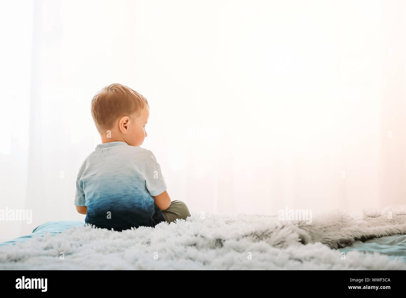 Little boy with autistic disorder sitting on bed at home Stock Photo ...
