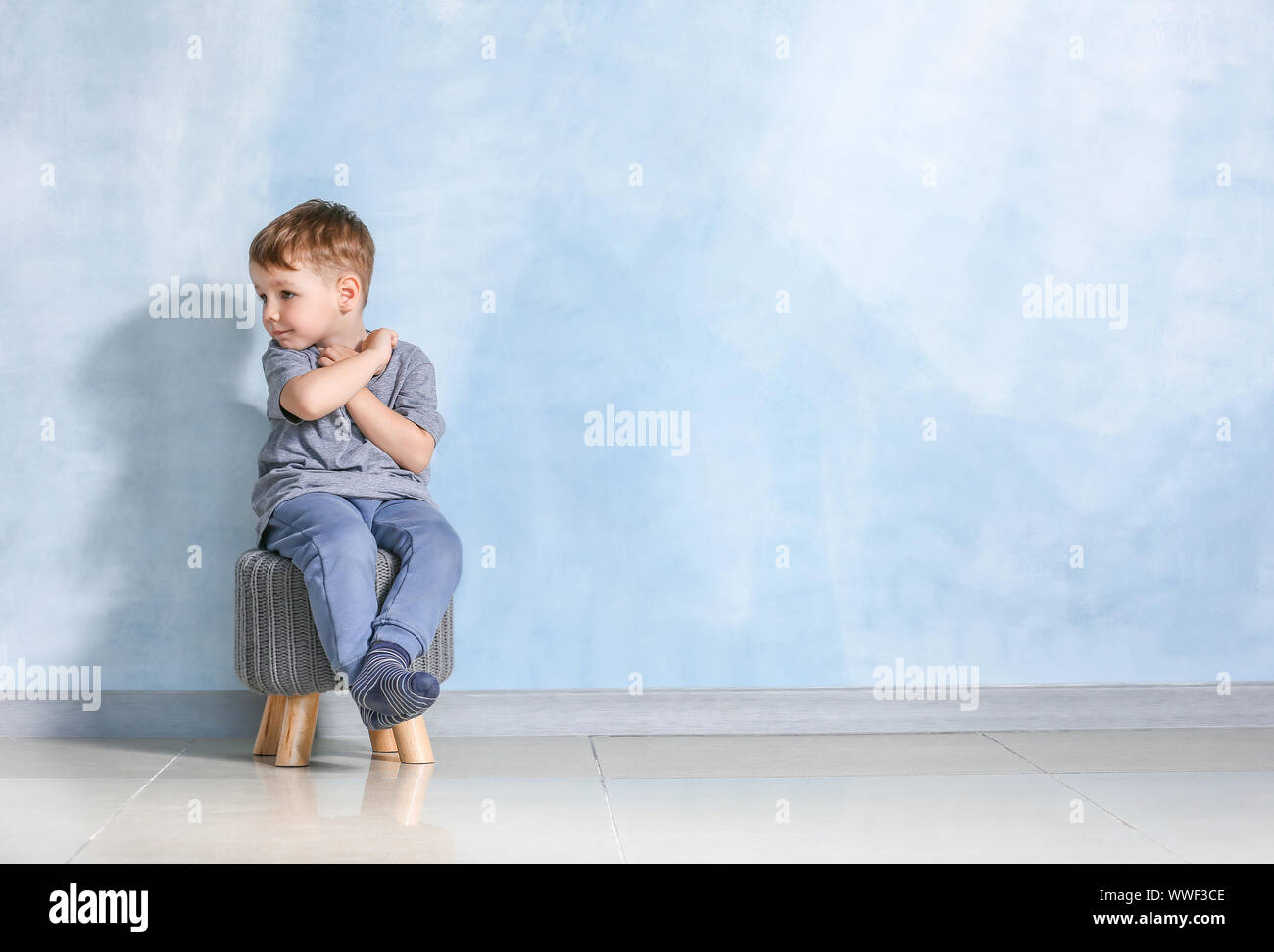 Little boy with autistic disorder sitting near light wall Stock Photo ...