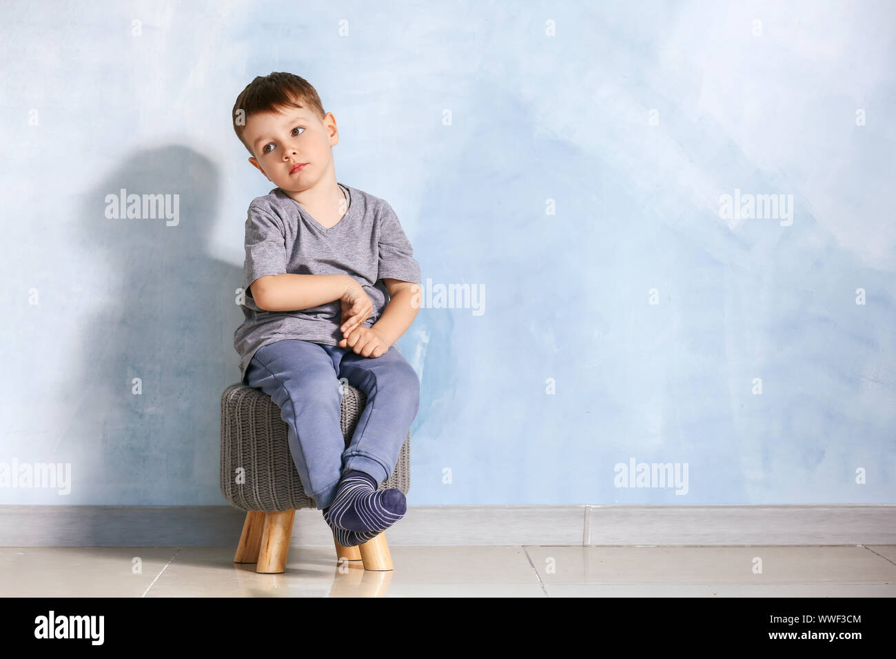 Little boy with autistic disorder sitting near light wall Stock Photo ...