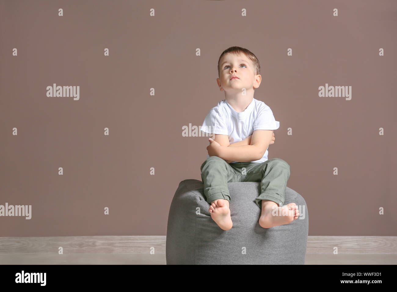 Little boy with autistic disorder sitting near color wall Stock Photo ...