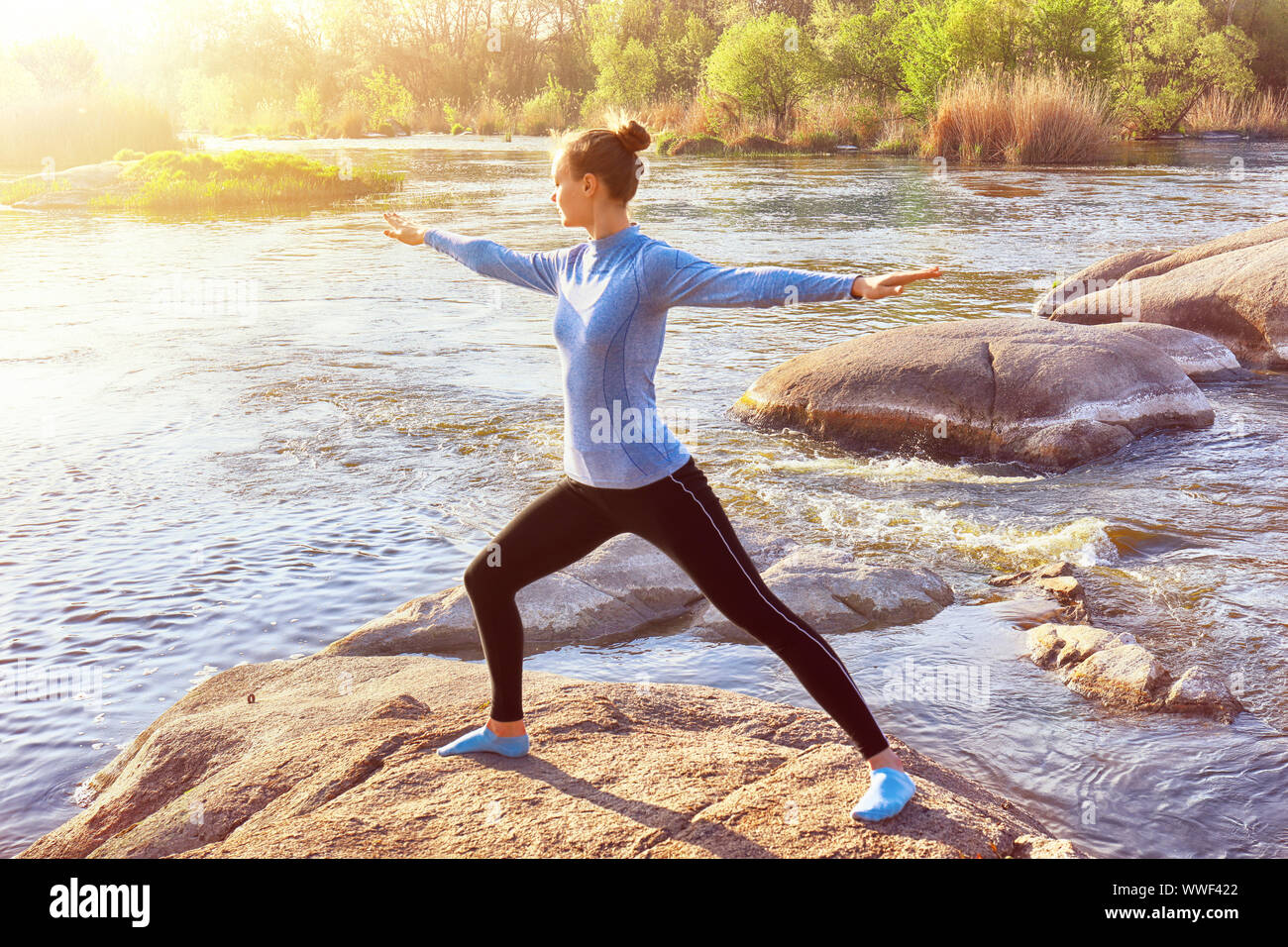 Beautiful young woman practicing yoga near river Stock Photo - Alamy