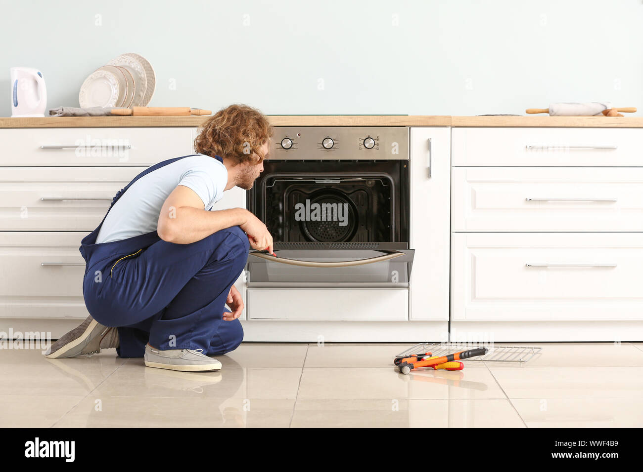 Worker repairing oven in kitchen Stock Photo - Alamy