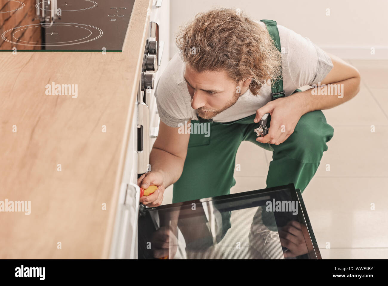 Worker repairing oven in kitchen Stock Photo - Alamy